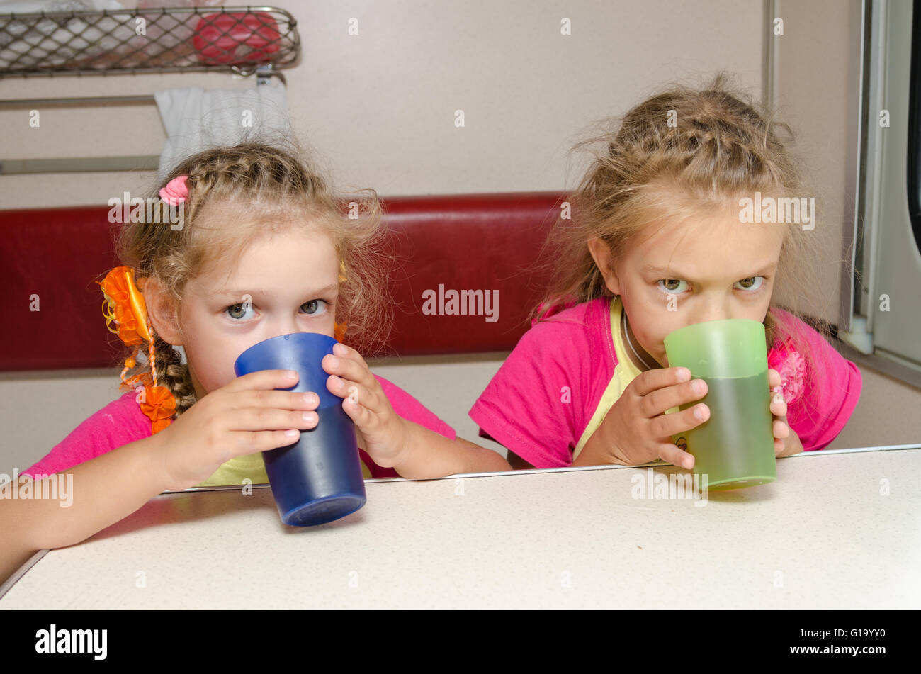 Two children drink tea in train at the table on the lower place in the ...