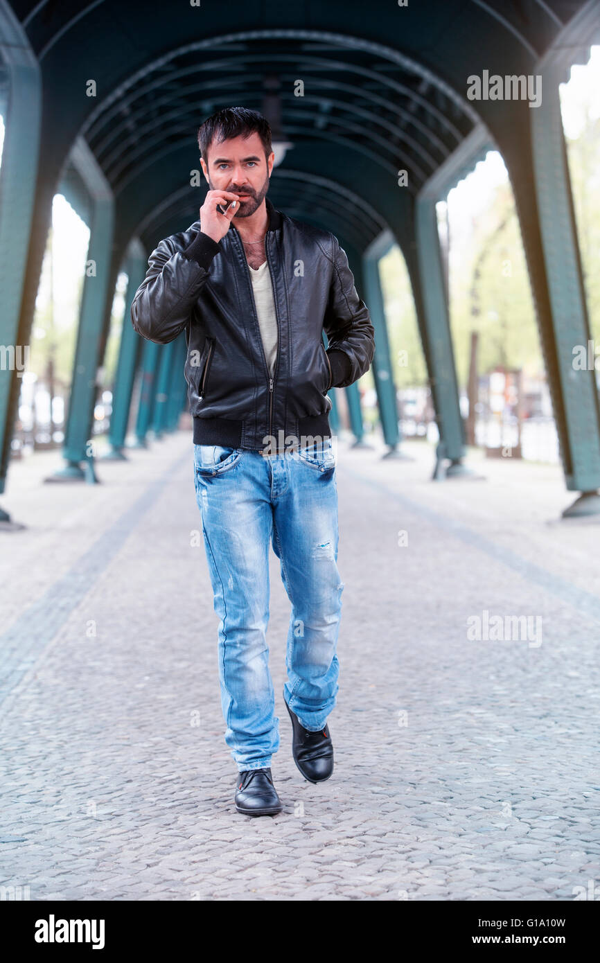 man in jeans walking the street and smoking a cigarette Stock Photo - Alamy