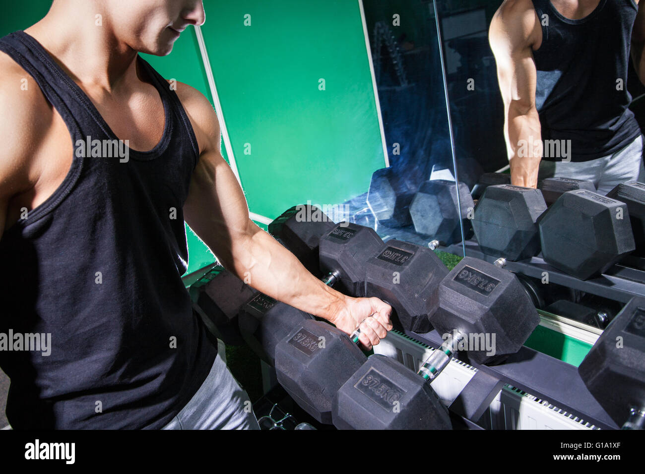 SIde view of handsome bodybuilder holding heavy dumbbell Stock Photo ...