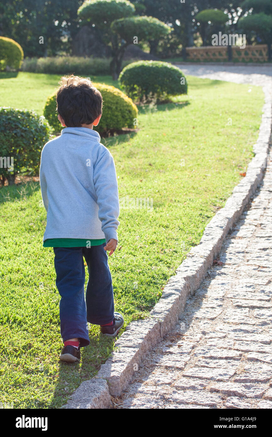 Boy walks on grass sidewalk besides road Stock Photo - Alamy