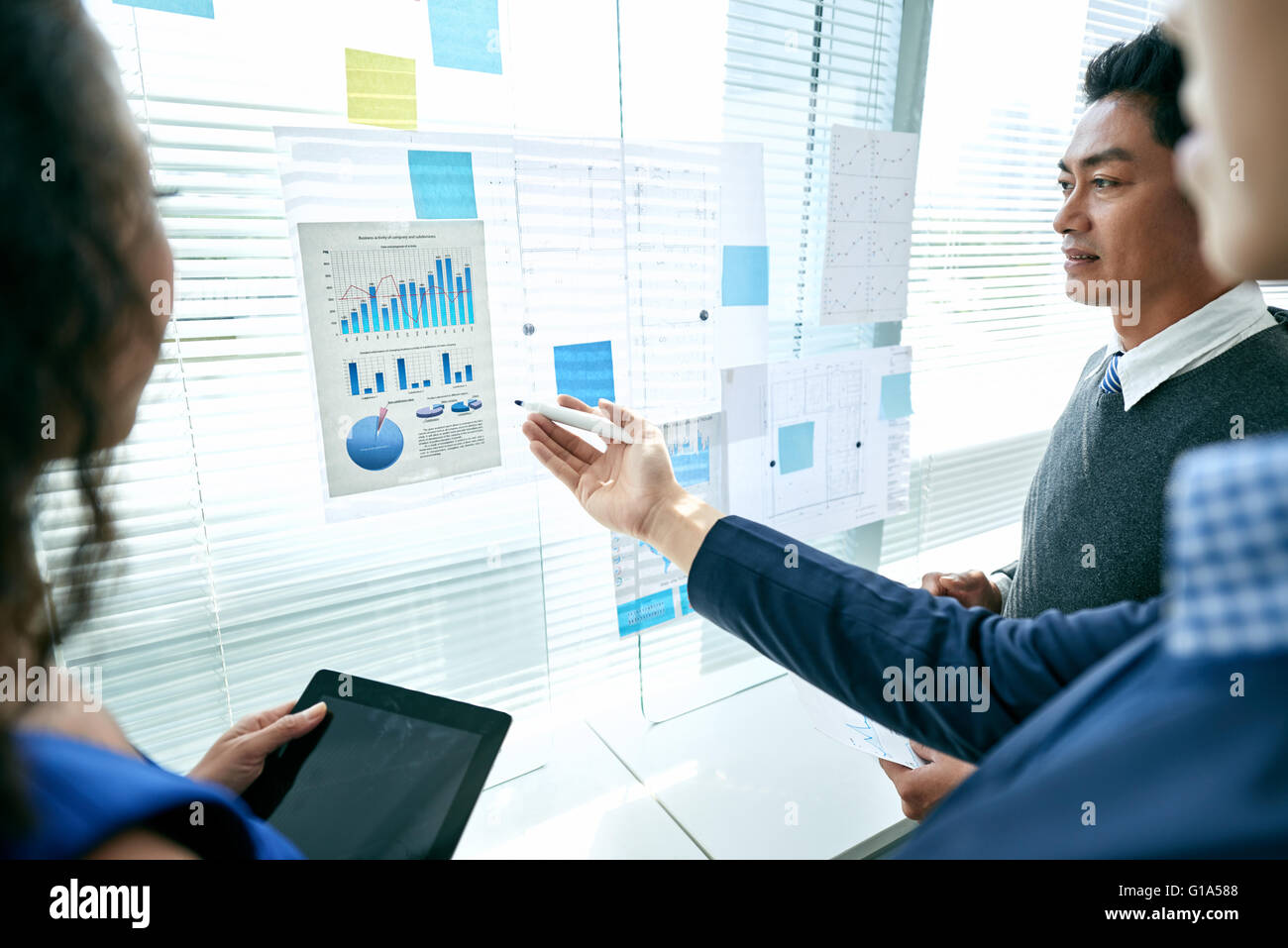 Business people discussing diagram on the wall Stock Photo - Alamy