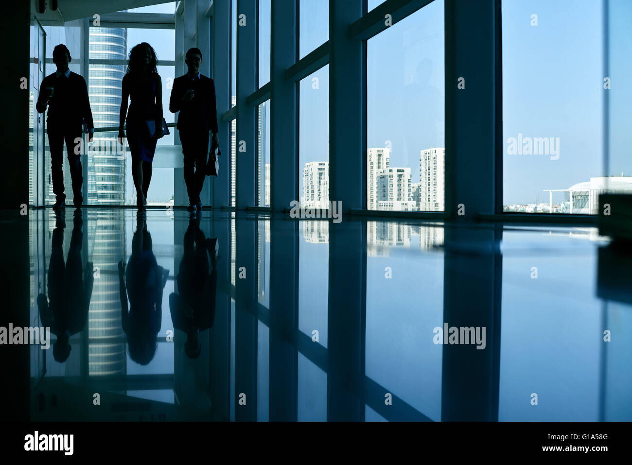 Business people walking along dark office corridor Stock Photo - Alamy