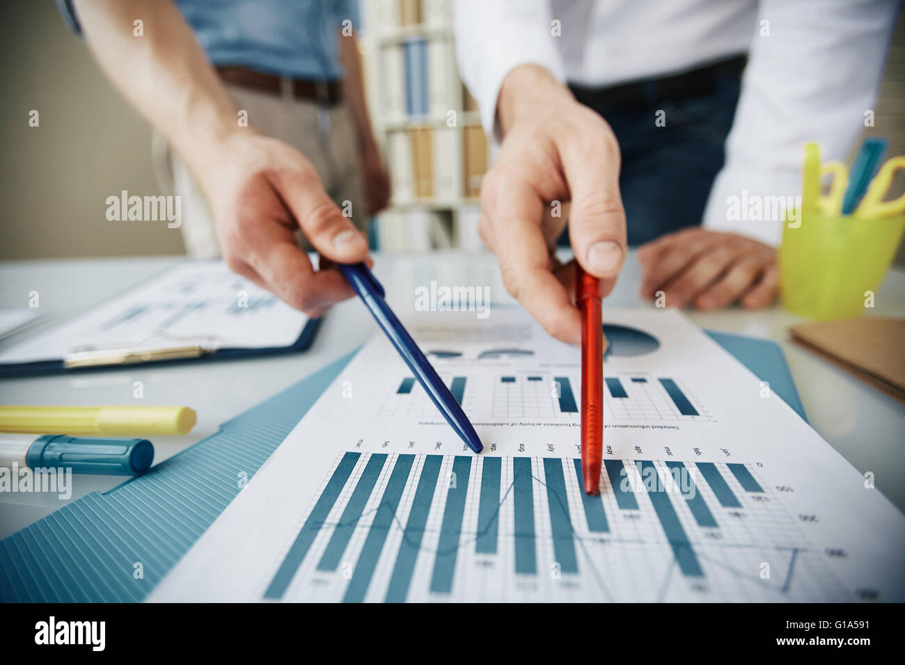 Two office workers pointing at chart in business document during ...