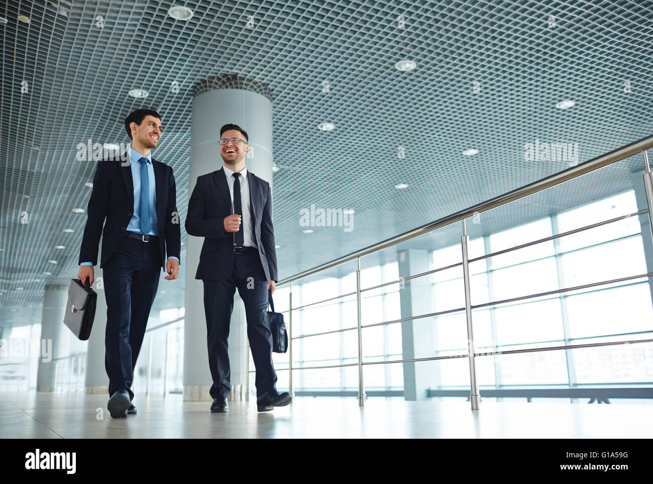 Successful business leaders in suits walking down corridor of office ...