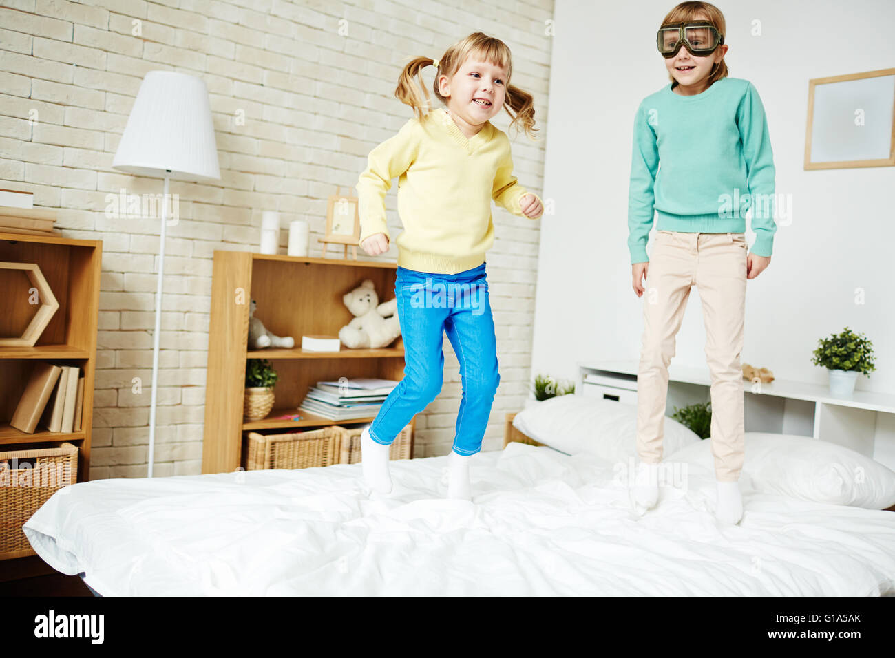 Little girls jumping on bed at home Stock Photo - Alamy