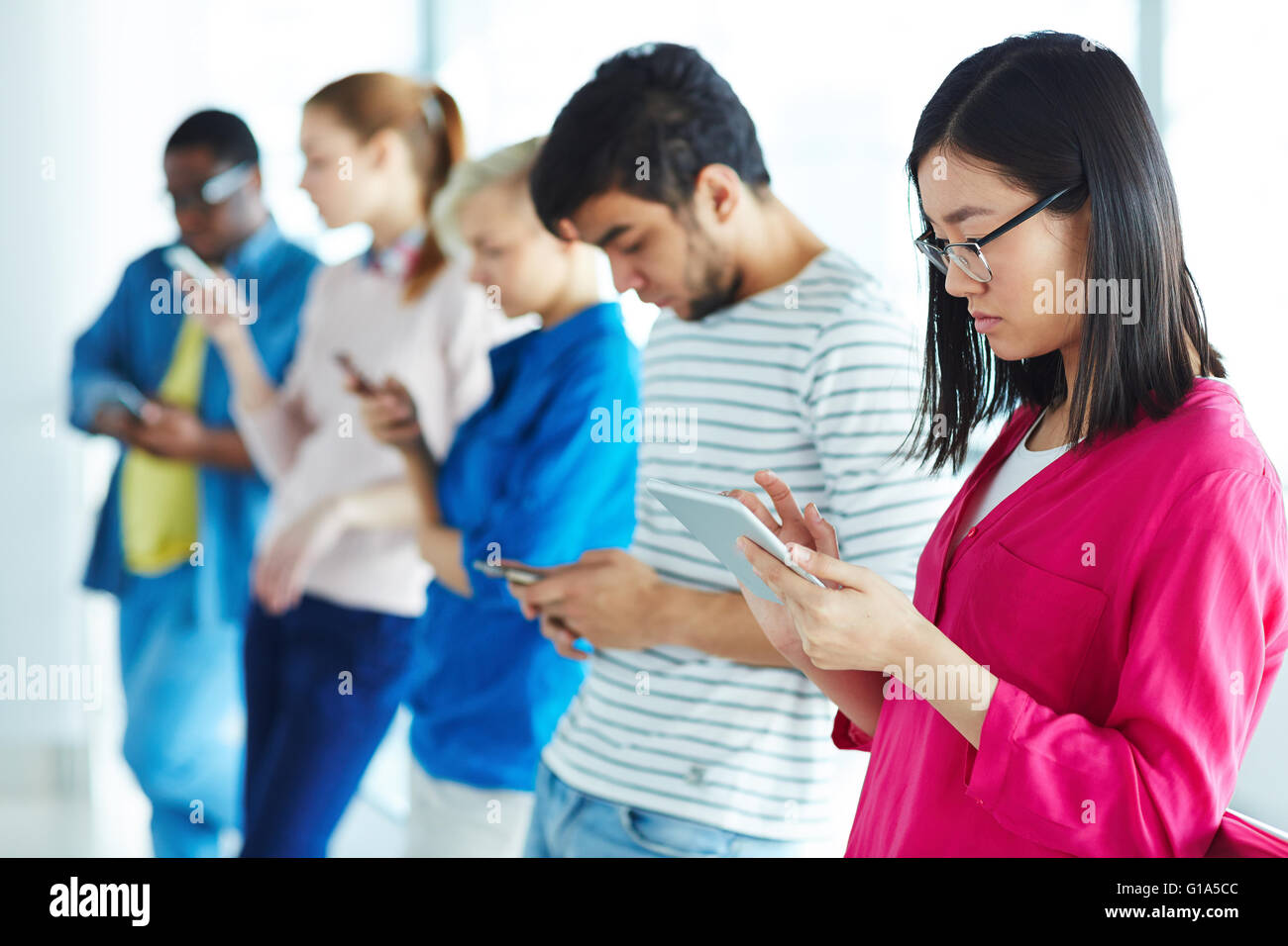 Group of contemporary multi-ethnic students using gadgets Stock Photo ...