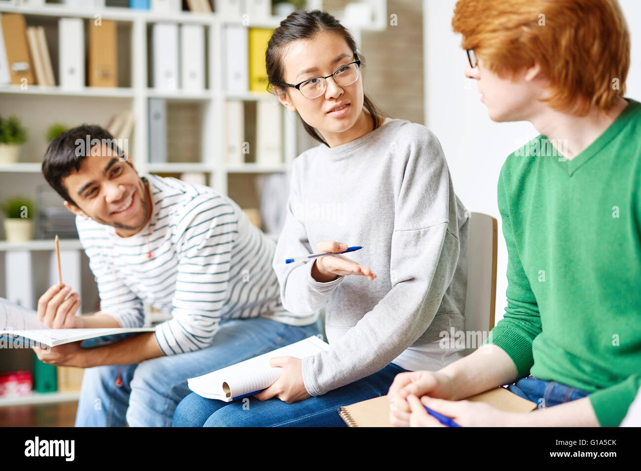 Asian student looking at group-mate while explaining her idea Stock ...