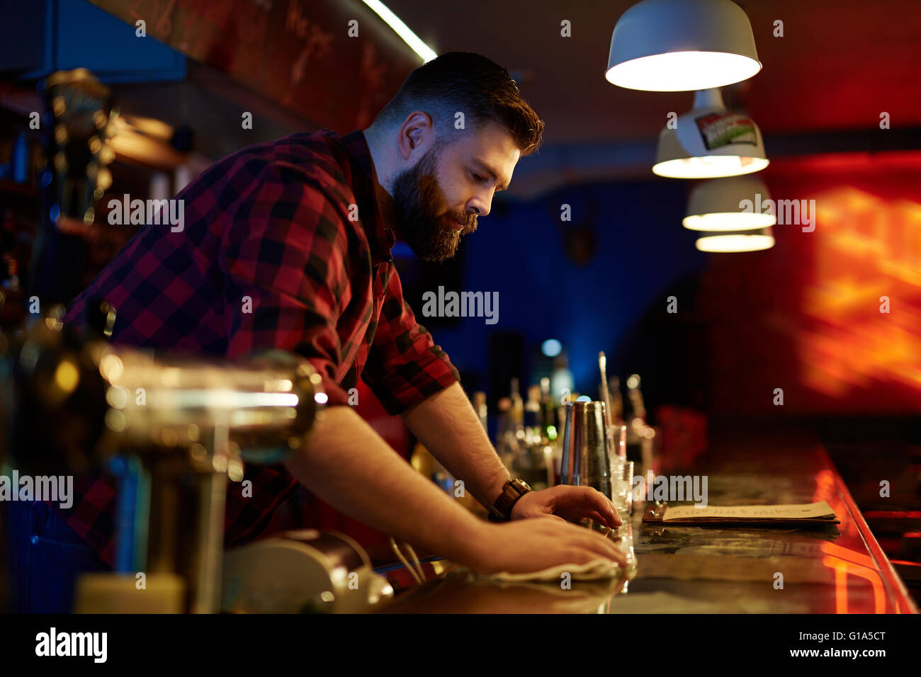 Serious young barman wiping bar counter Stock Photo - Alamy