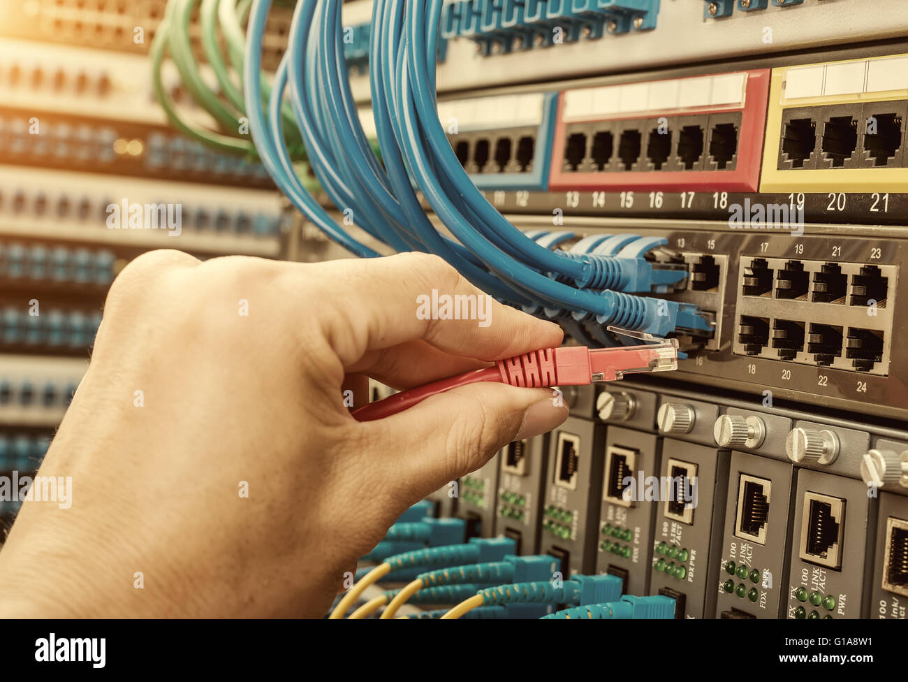 man working in network server room with fiber optic hub for digital ...