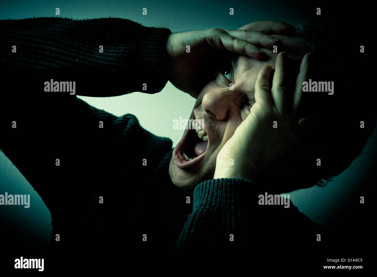 man with hands on his head screaming, concept for madness and insanity ...