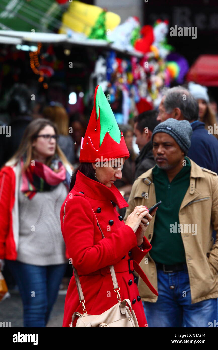 Woman wearing elf costume checks messages on her smartphone in ...