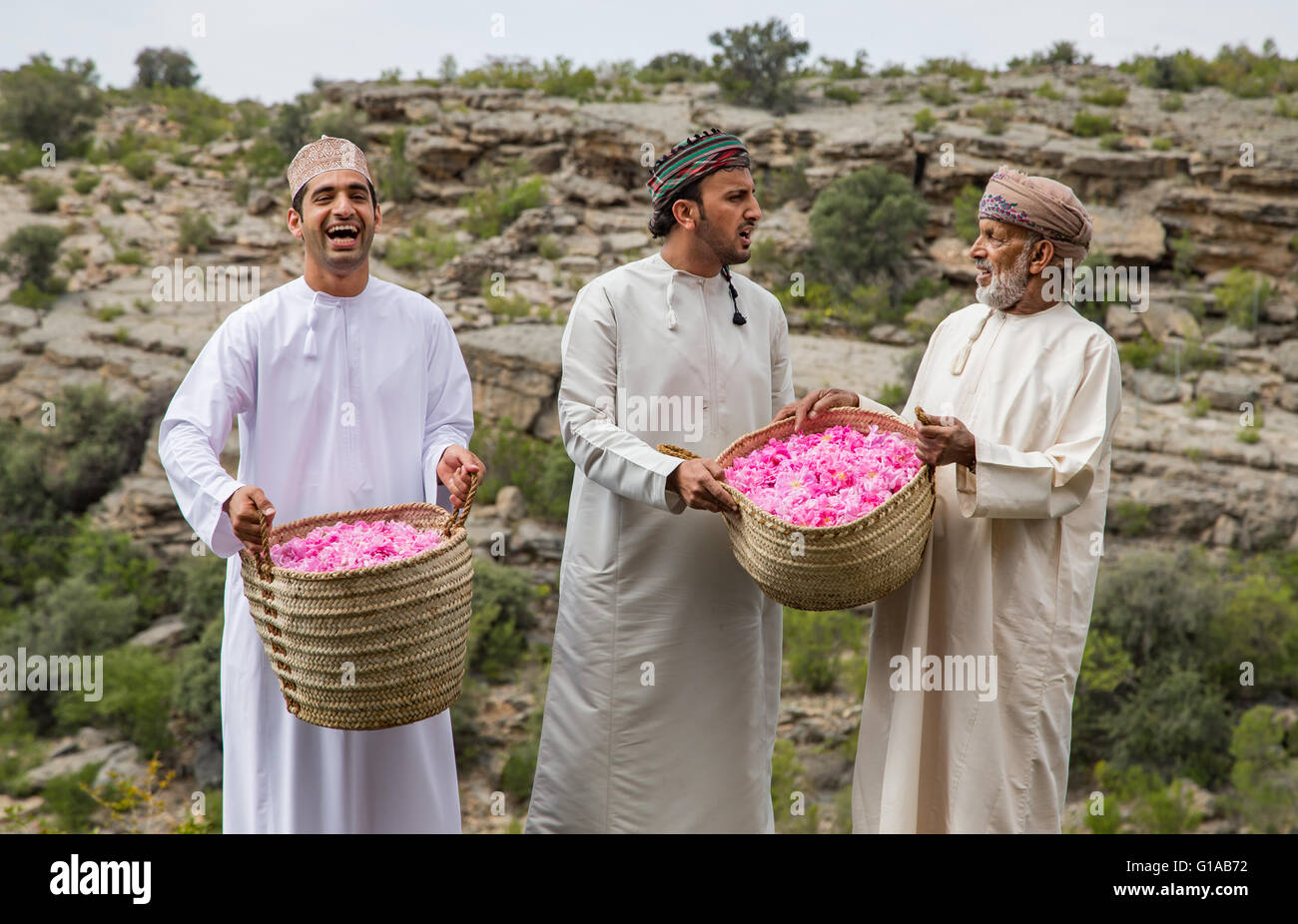 Omani men in traditional clothing showing off basket full of rose ...