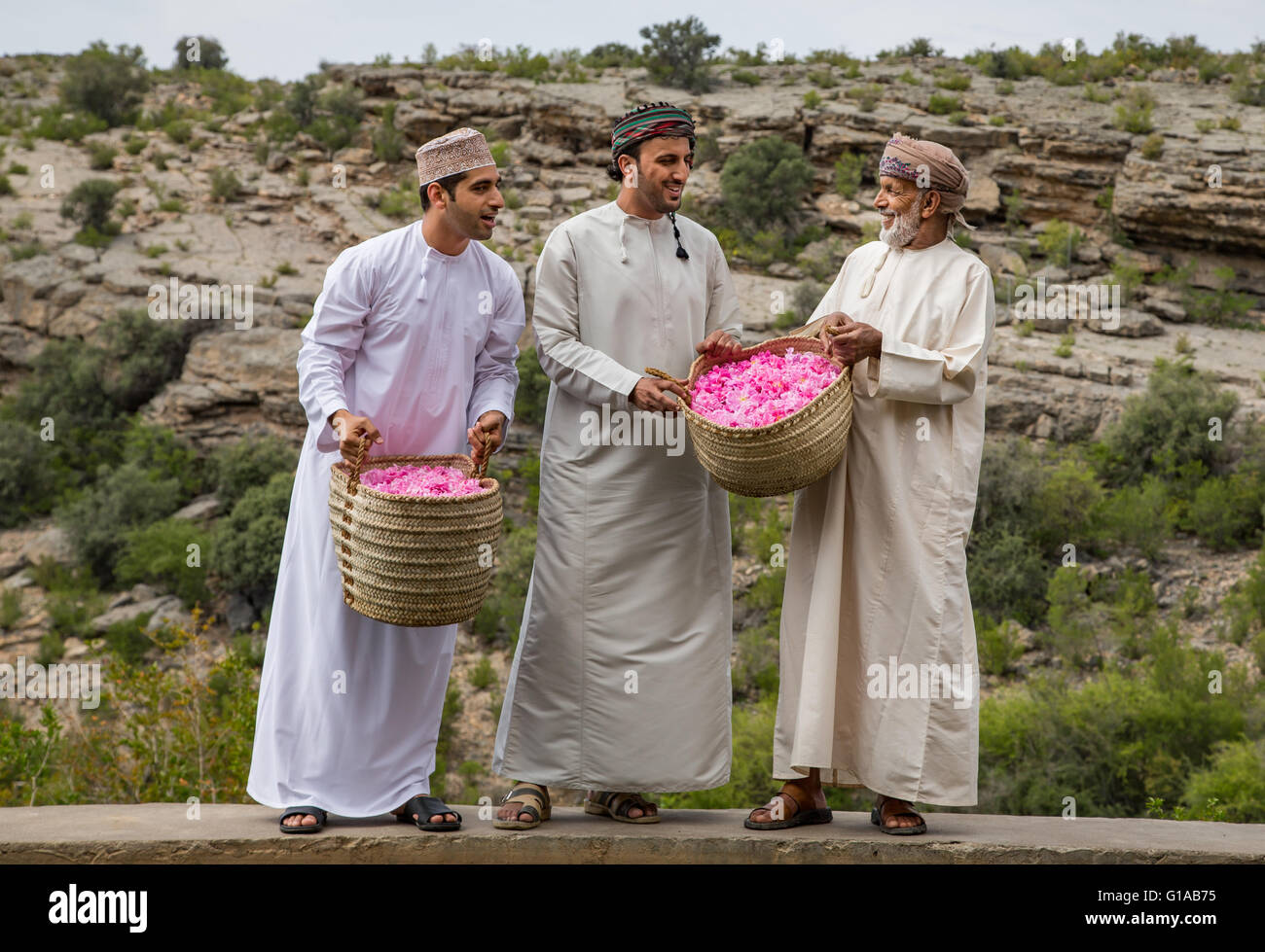 Omani men in traditional clothing showing off basket full of rose ...