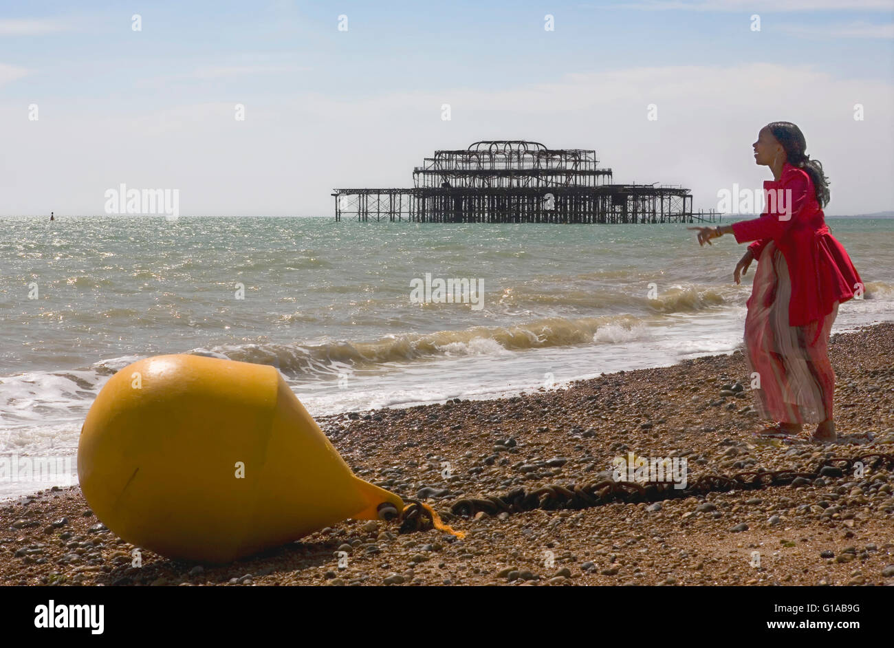 A lady enjoys the beach, with beyond, the sad remains of the West Pier ...