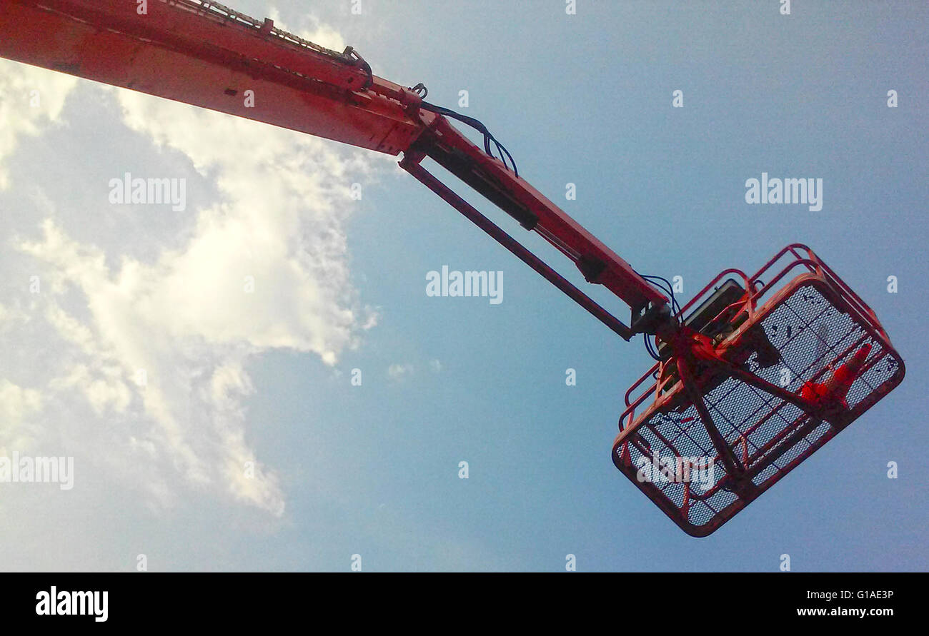 orange working platform in the air against a cloudy blue sky with a ...