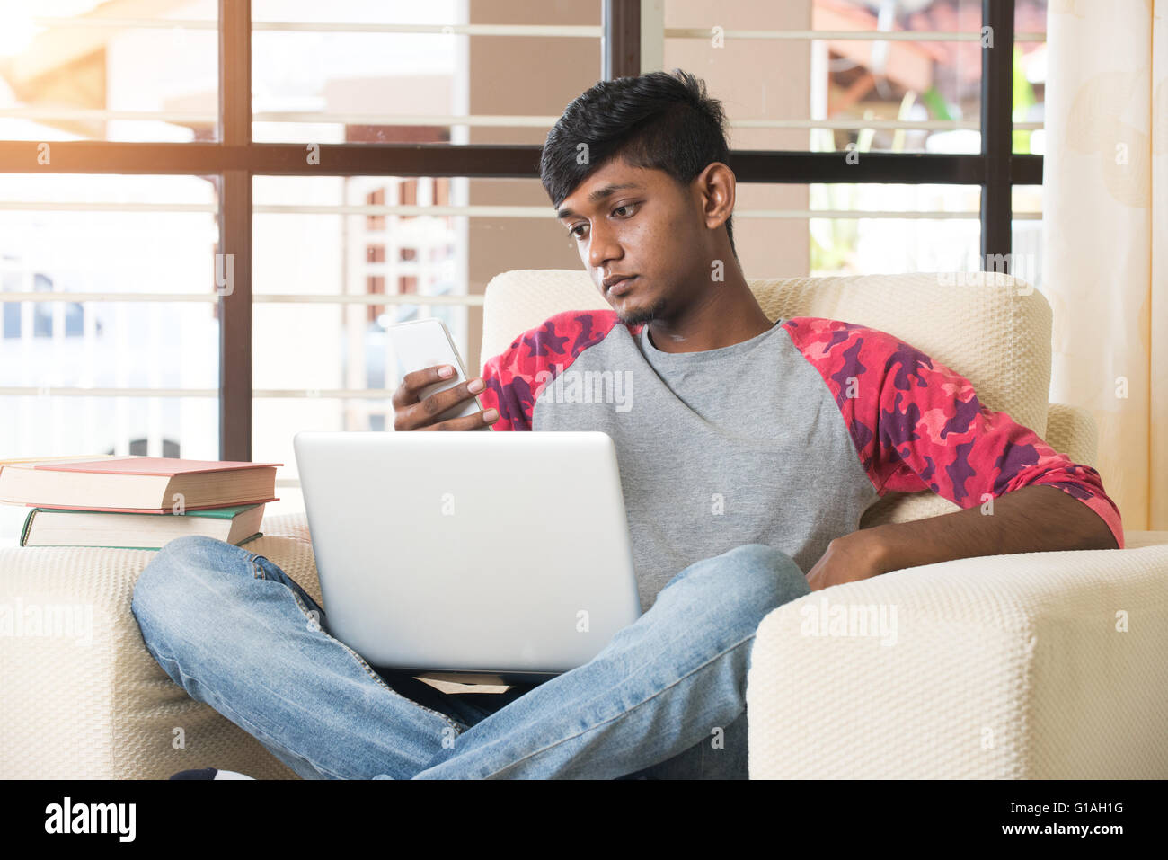 teenage indian male using laptop and phone Stock Photo - Alamy