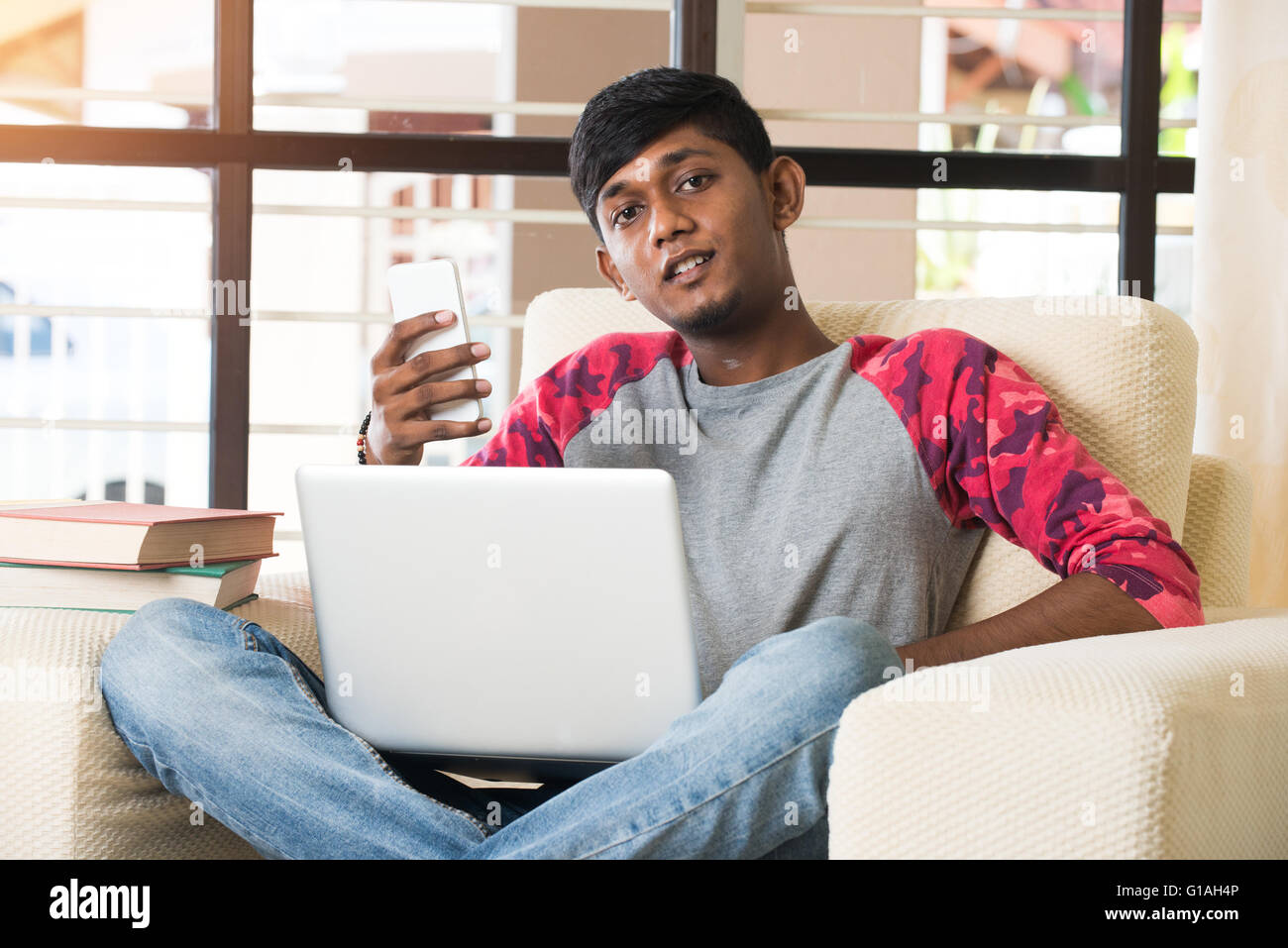 teenage indian male using laptop and phone Stock Photo - Alamy