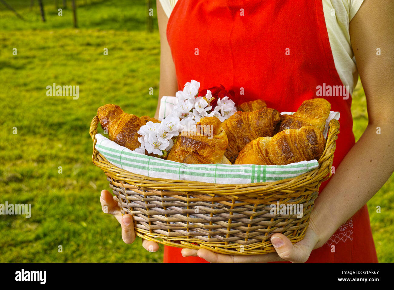 Young woman in red apron holding a wicker basket of fresh baked ...