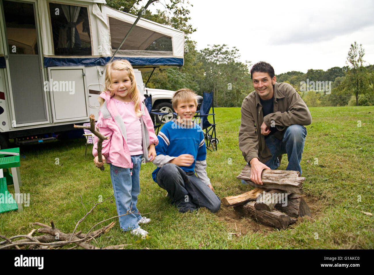 Family camping outdoors around a fancy pop-up trailer Stock Photo - Alamy