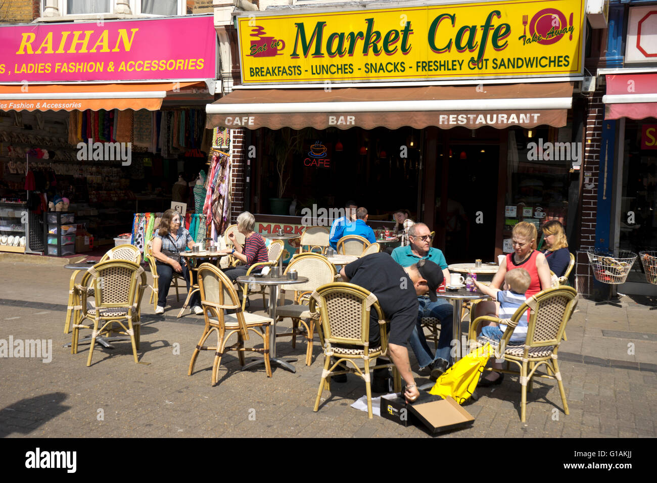 People sit in an outdoor cafe in a pedestrianized street in ...