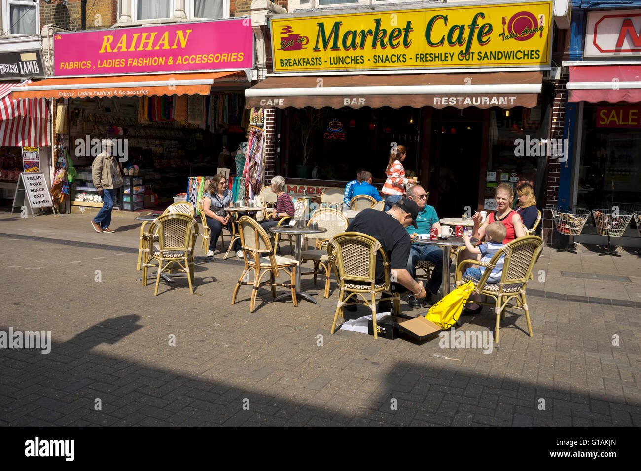 People sit in an outdoor cafe in a pedestrianized street in ...
