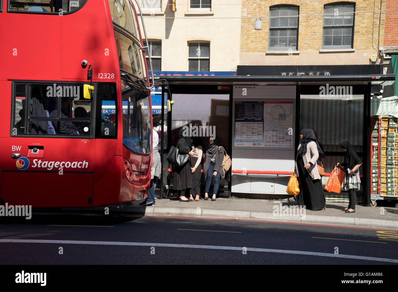 Muslim and African passengers waiting for a bus in Whitechapel, London ...