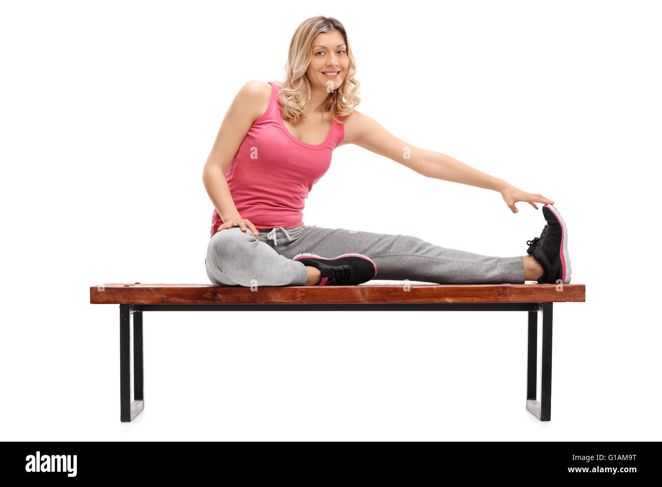 Cheerful female athlete stretching her leg seated on a bench isolated ...