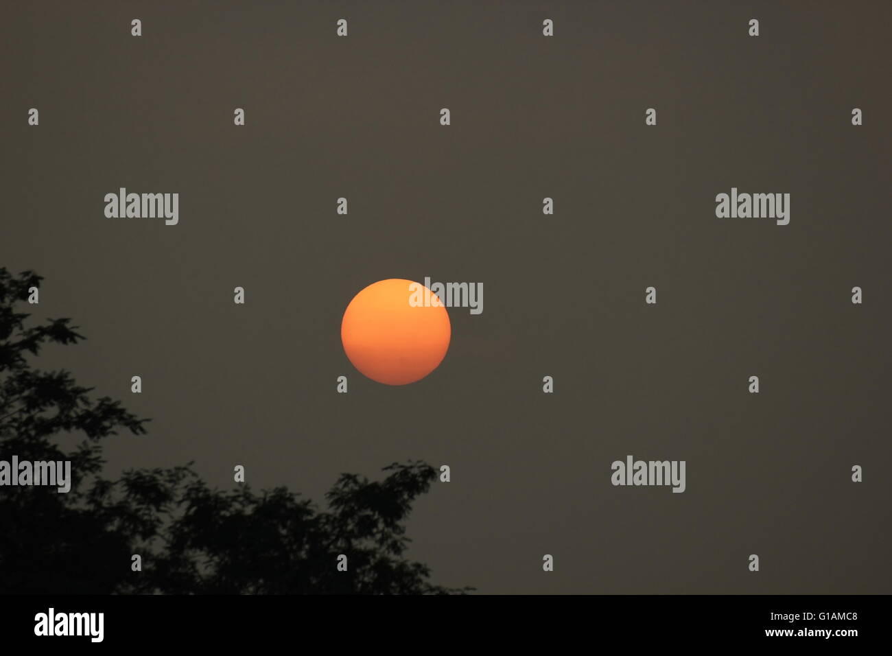 Deep orange sun in polluted sky Stock Photo - Alamy
