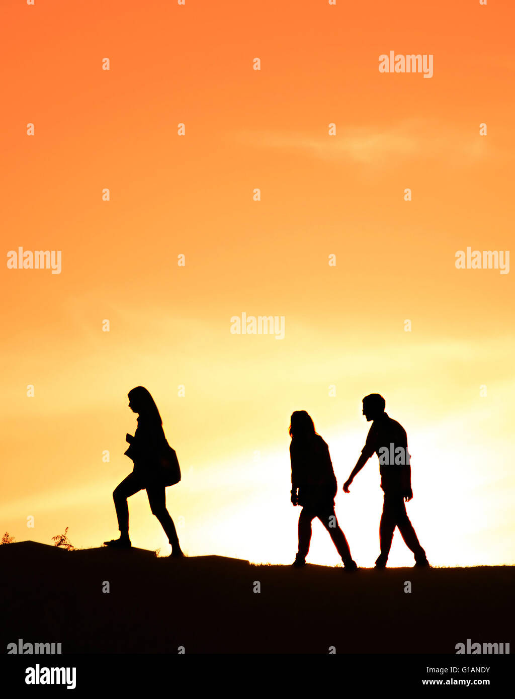 Three person walking at sunset on a hill Stock Photo - Alamy