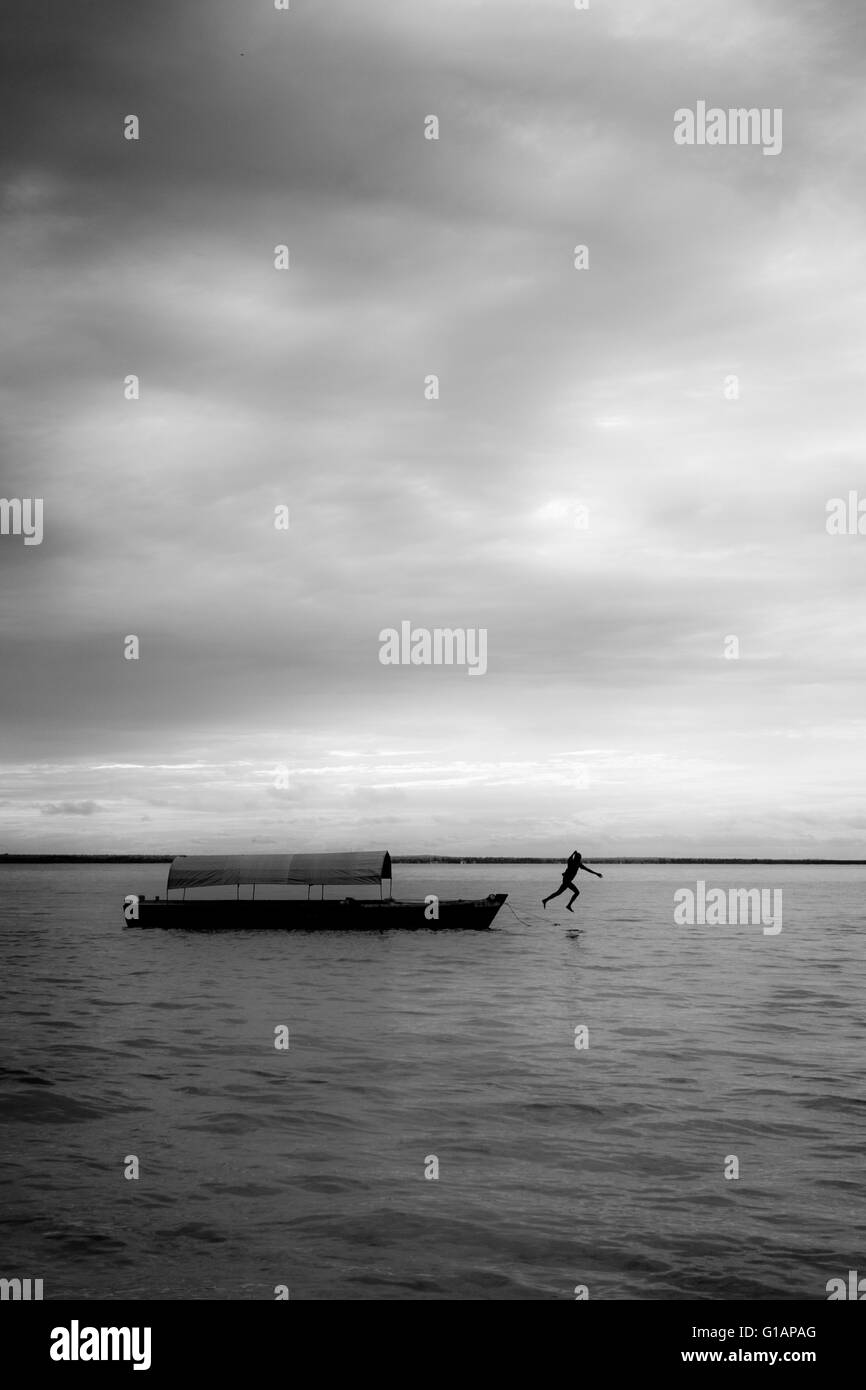 Two lone fishermen bail out their boat in the Indian Ocean, Zanzibar ...