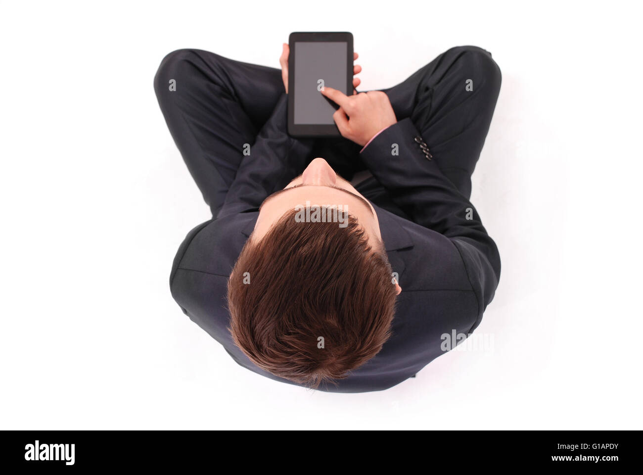 Boy in black suit sit and hold tablet PC isolated on white. Shallow ...
