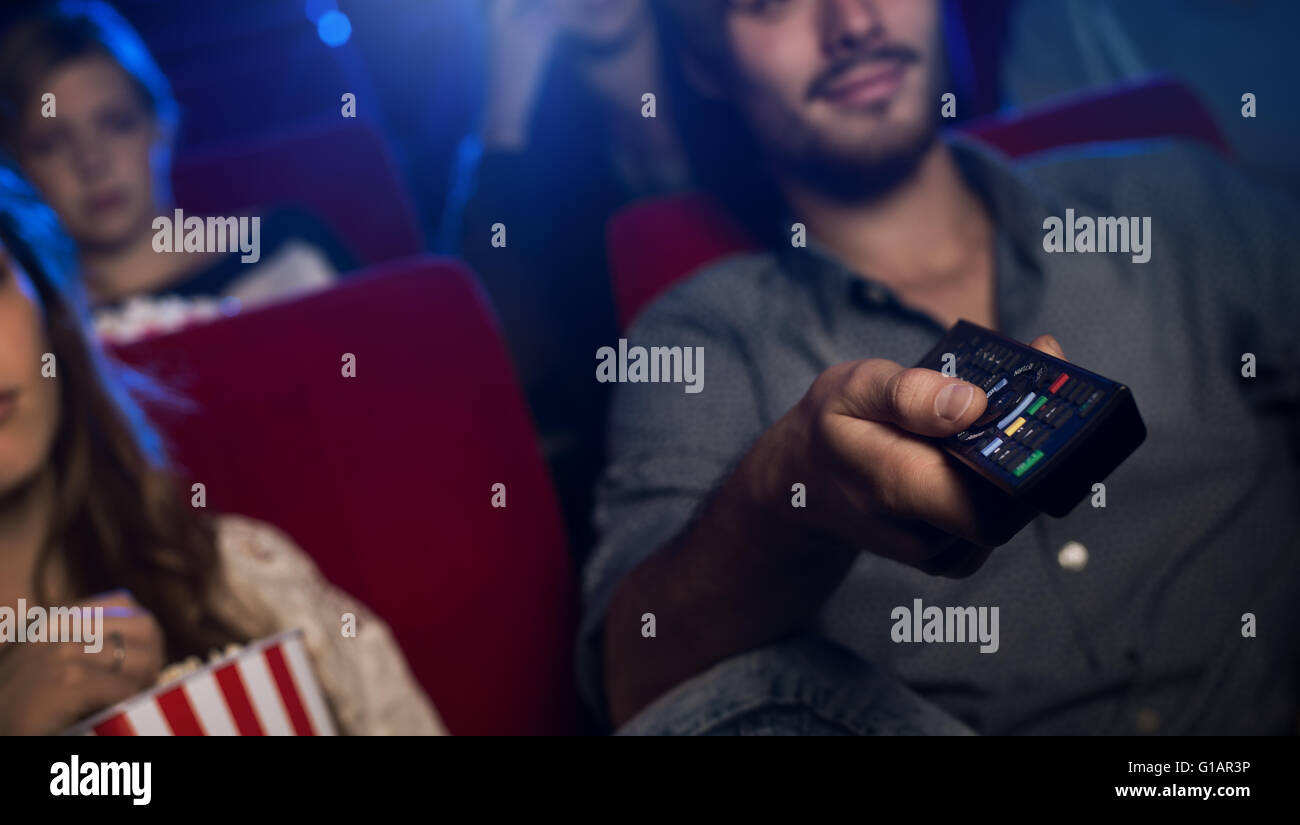 Group of friends watching a movie together, a man is holding a remote ...