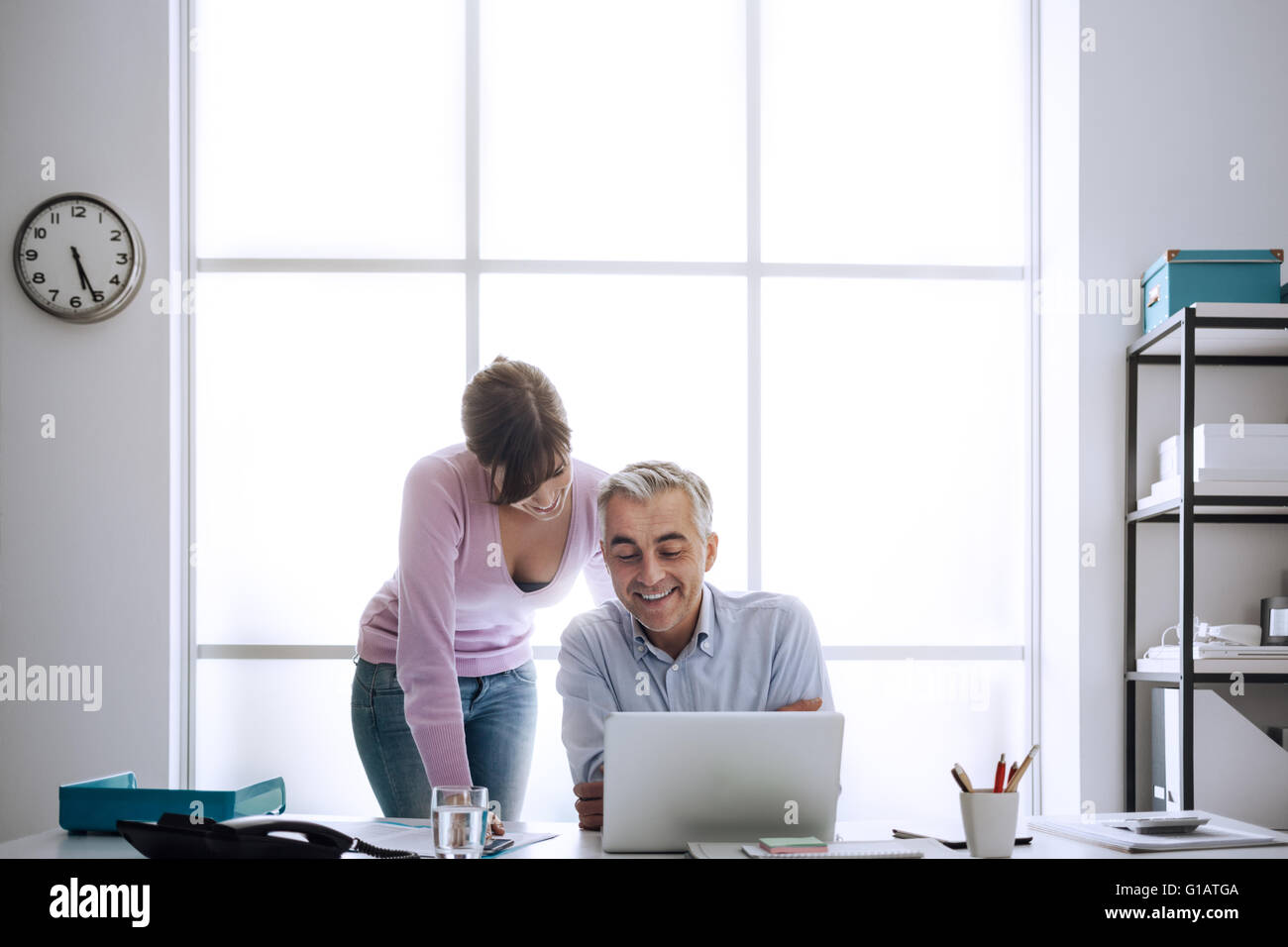 Executive working at office desk with his assistant, they are using a ...