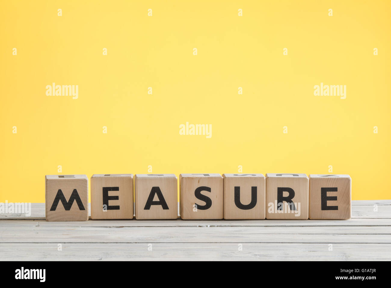Measure sign with wooden cubes on a yellow background Stock Photo - Alamy