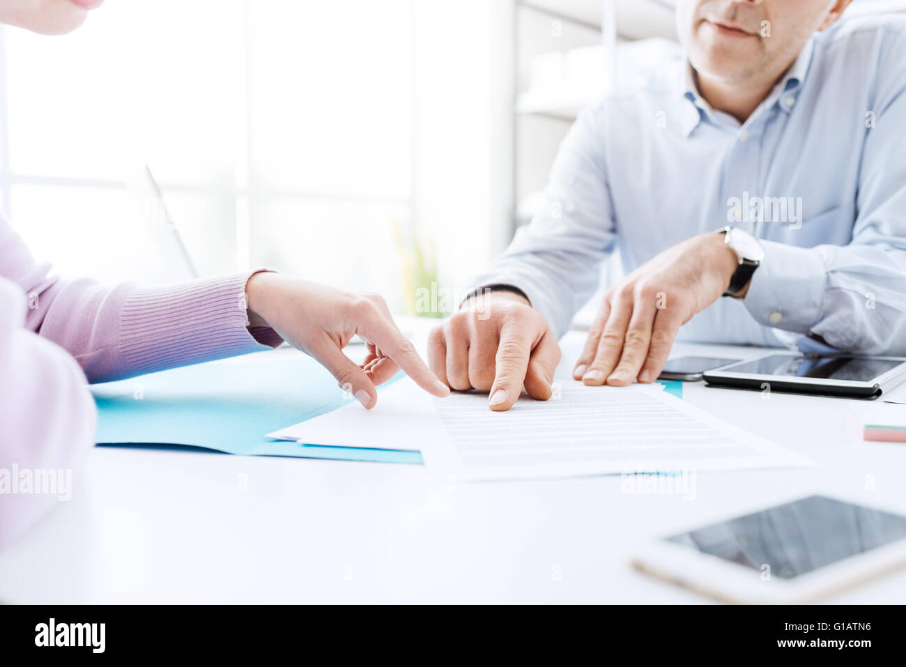 Business people negotiating a contract, they are pointing on a document ...