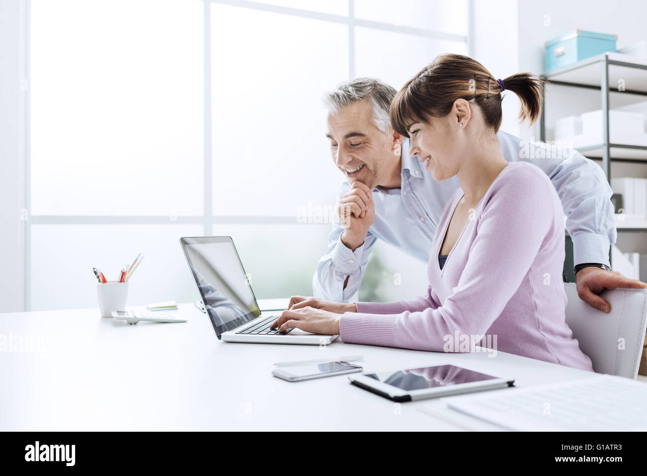 Business people working at office desk, a woman is using a laptop and ...
