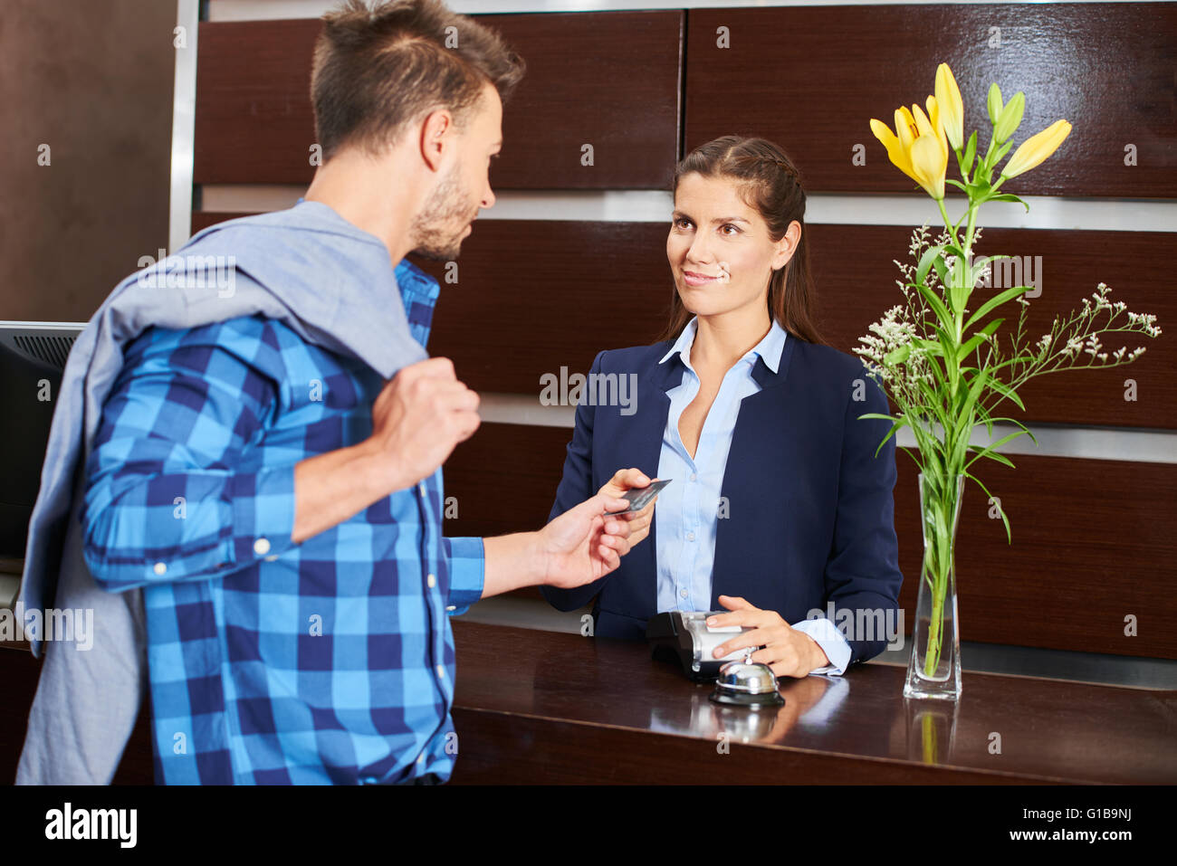 Male hotel guest paying with his credit card at reception Stock Photo ...