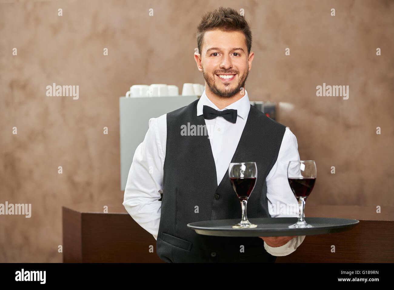 Smiling waiter in uniform serving red wine in a hotel restaurant Stock ...