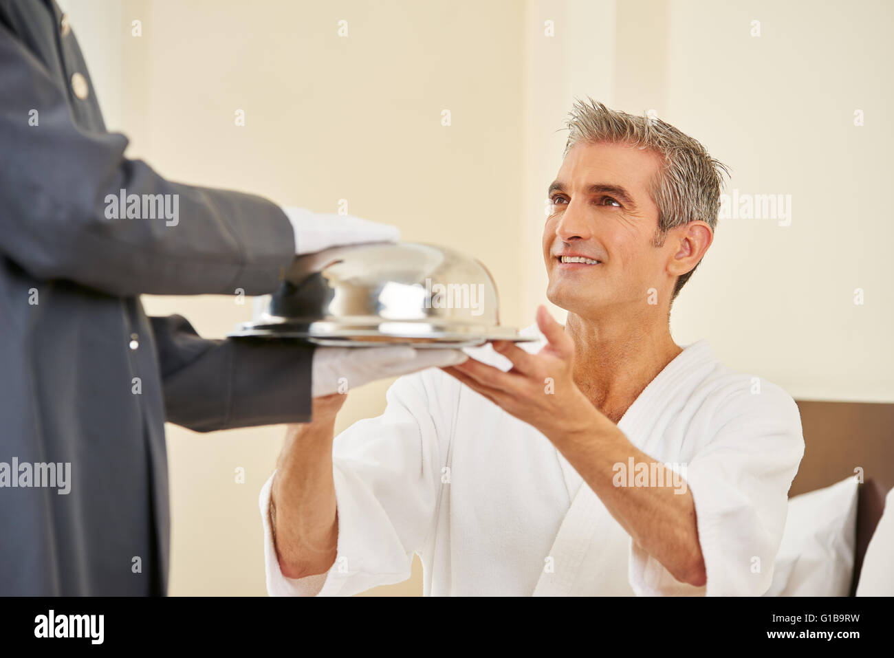 Hotel page bringing food as room service to an elderly man in a hotel ...