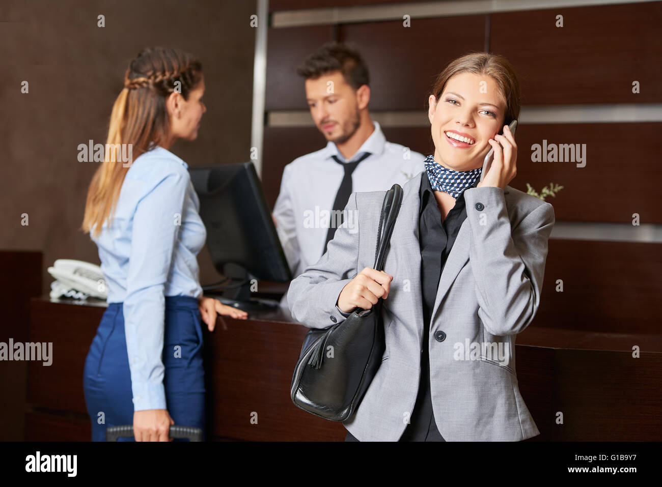 Business woman making phone call at hotel reception after check-in ...