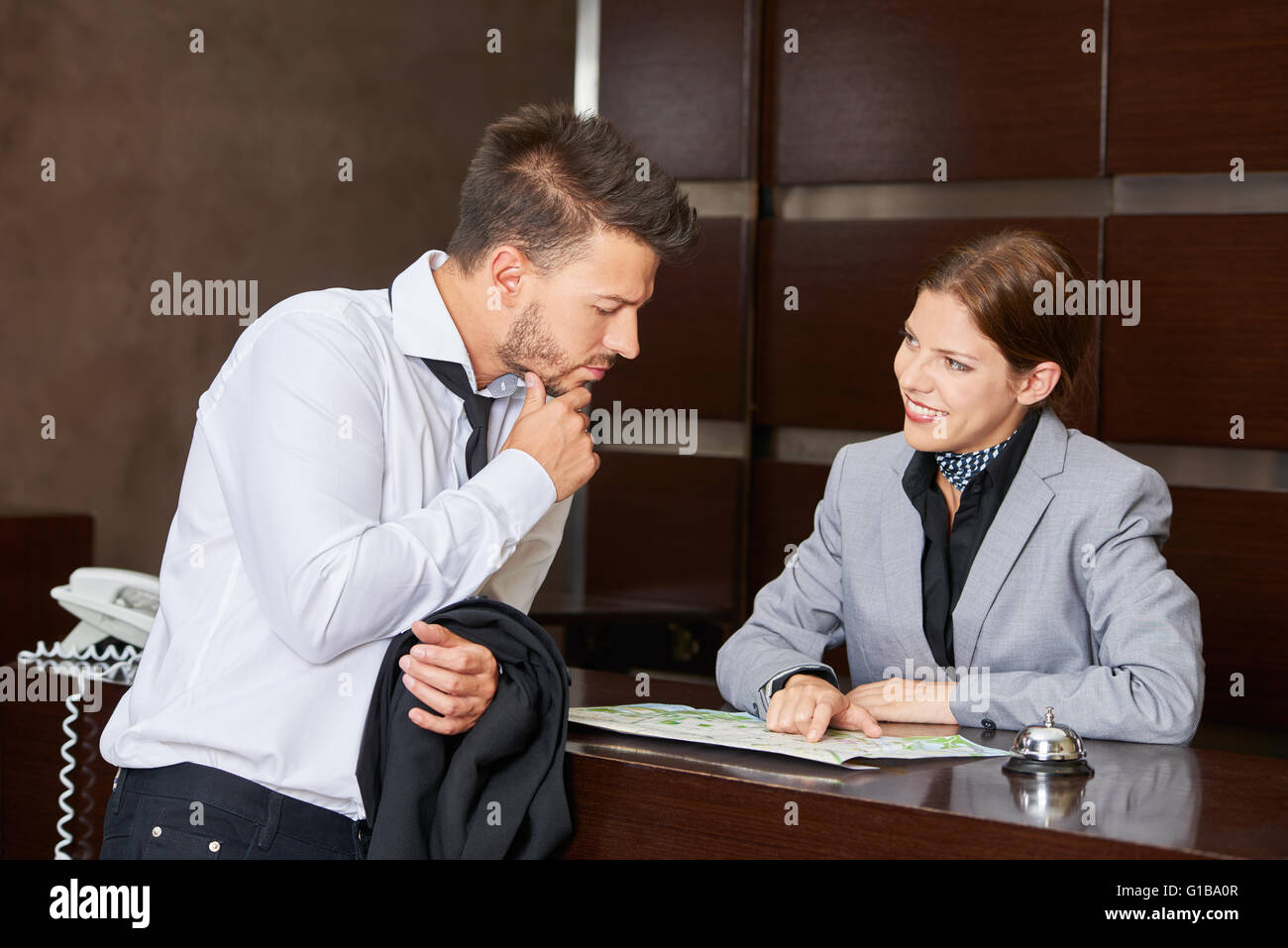 Receptionist in hotel giving advice to guest with a city map Stock ...