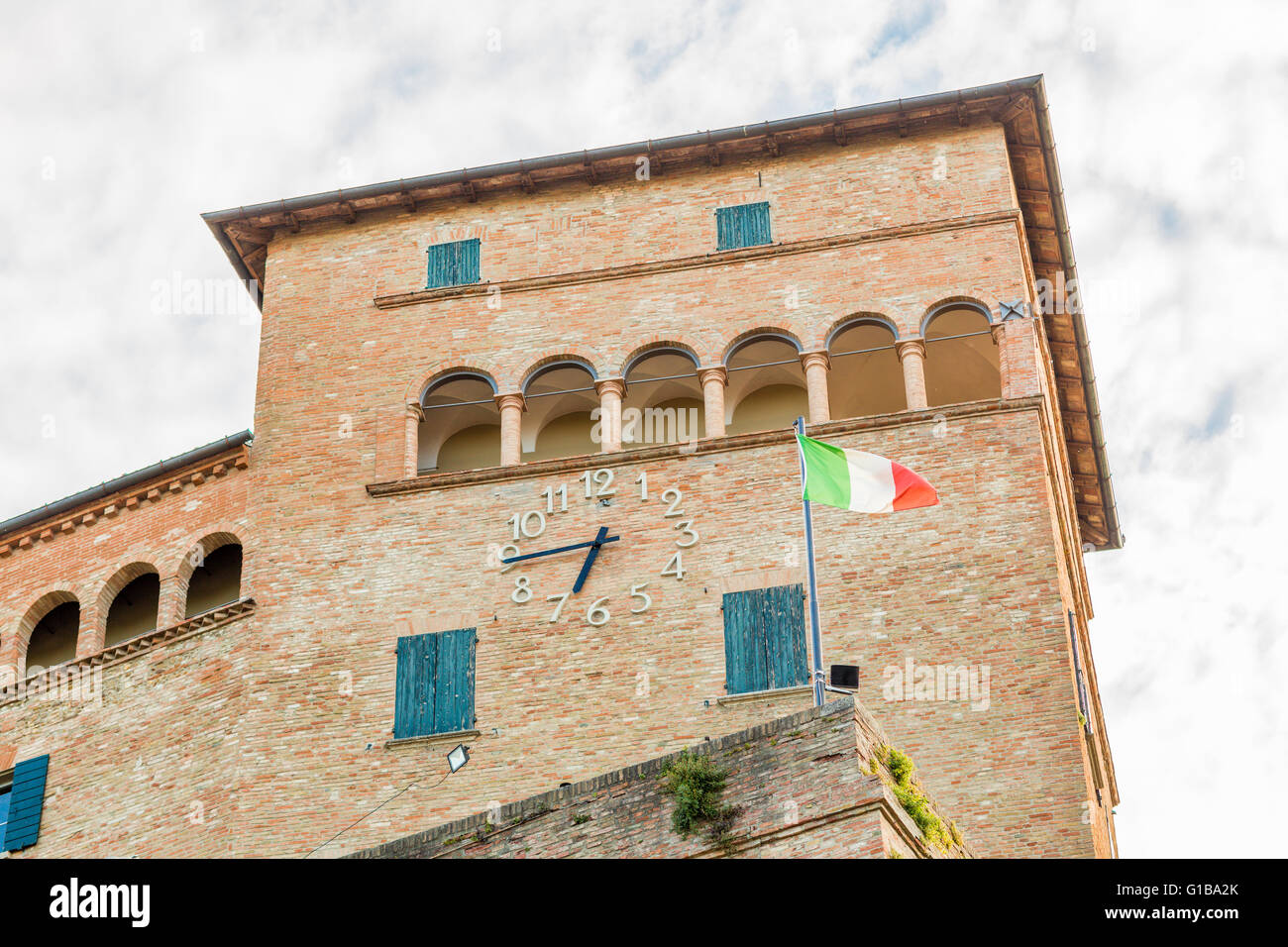 medieval castle tower with arches with clock and waving Italian flag ...