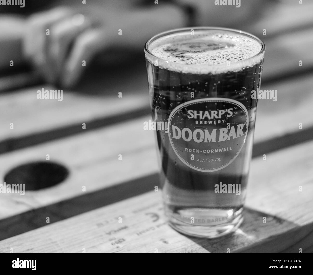 Pint of well known beer seen on a wooden bench in a beer garden in mid ...