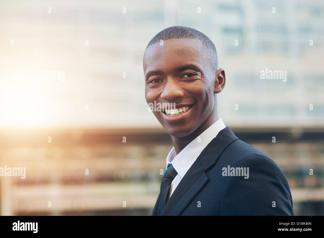 Portrait of a confident young businessman smiling at the camera with ...