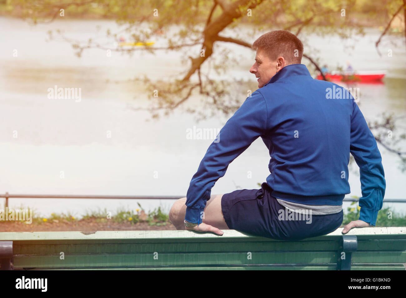 backside of man sitting on bench and looking at lake Stock Photo - Alamy