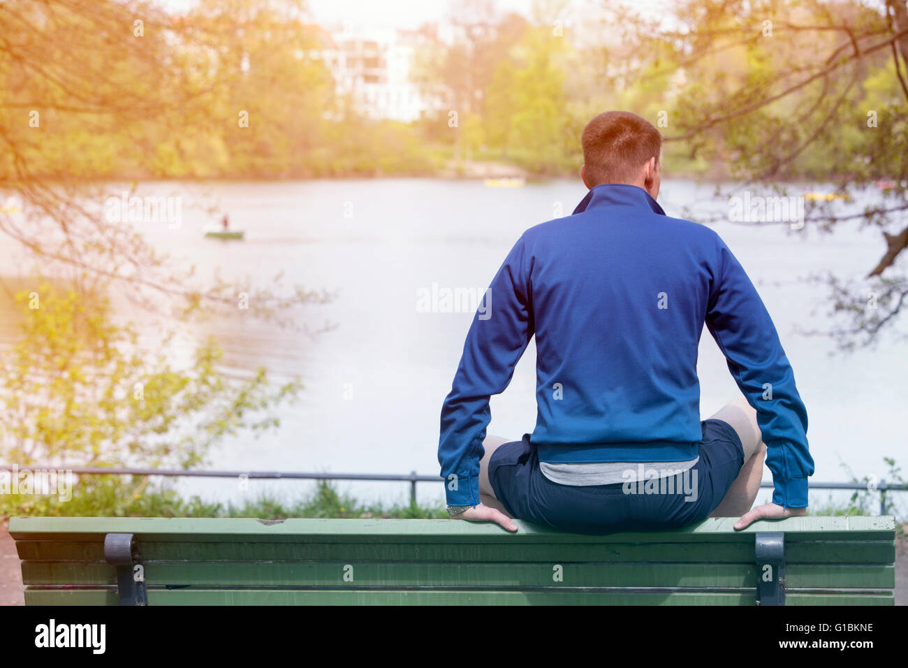 backside of man sitting on bench and looking at lake Stock Photo - Alamy