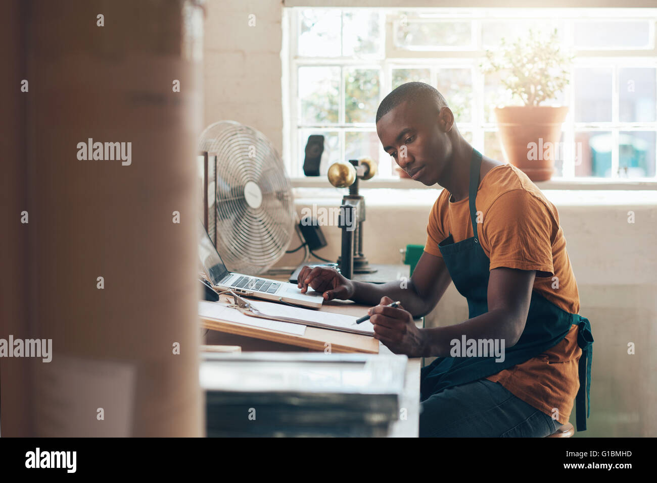 Handsome small business owner of African descent, sitting at his desk ...
