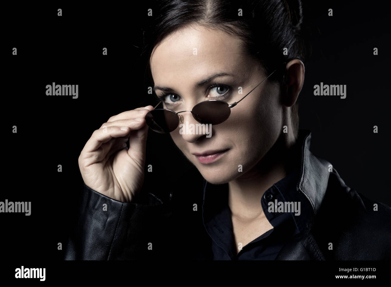 Attractive confident female agent in black leather coat adjusting ...