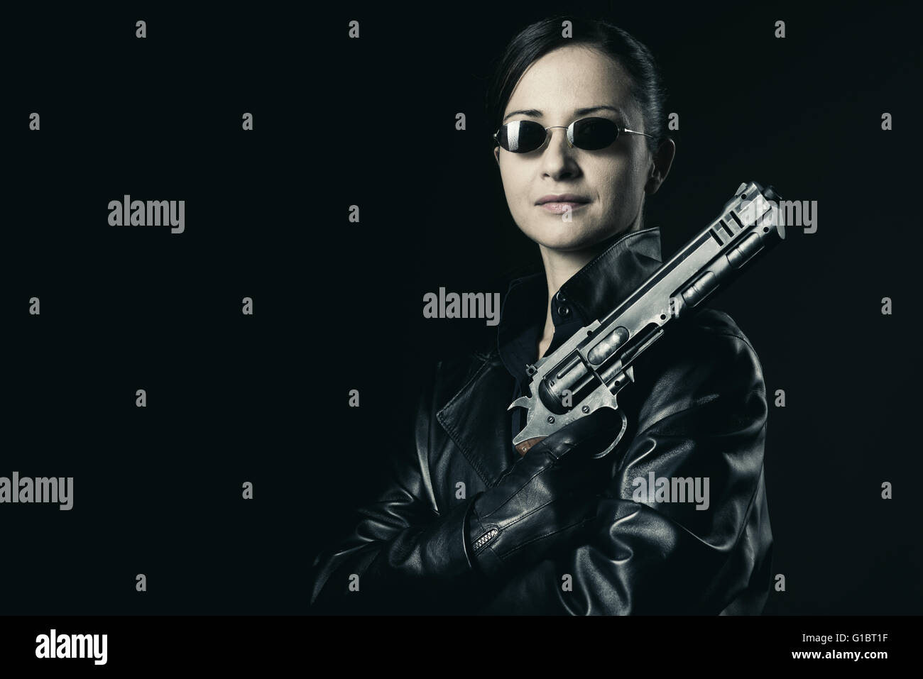 Attractive female agent in black leather coat and sunglasses holding a ...