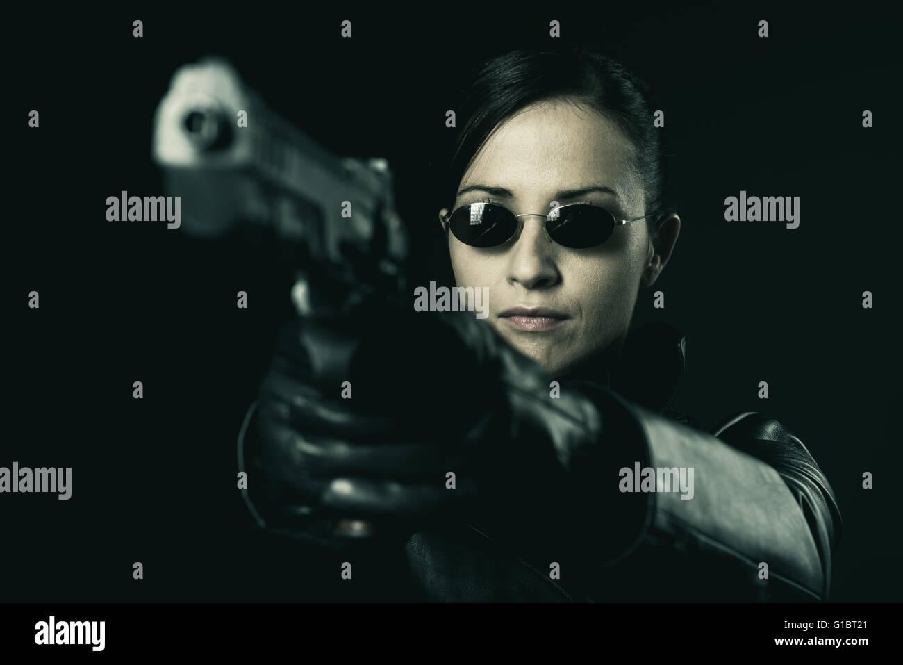 Attractive female criminal in black leather coat pointing a gun Stock ...